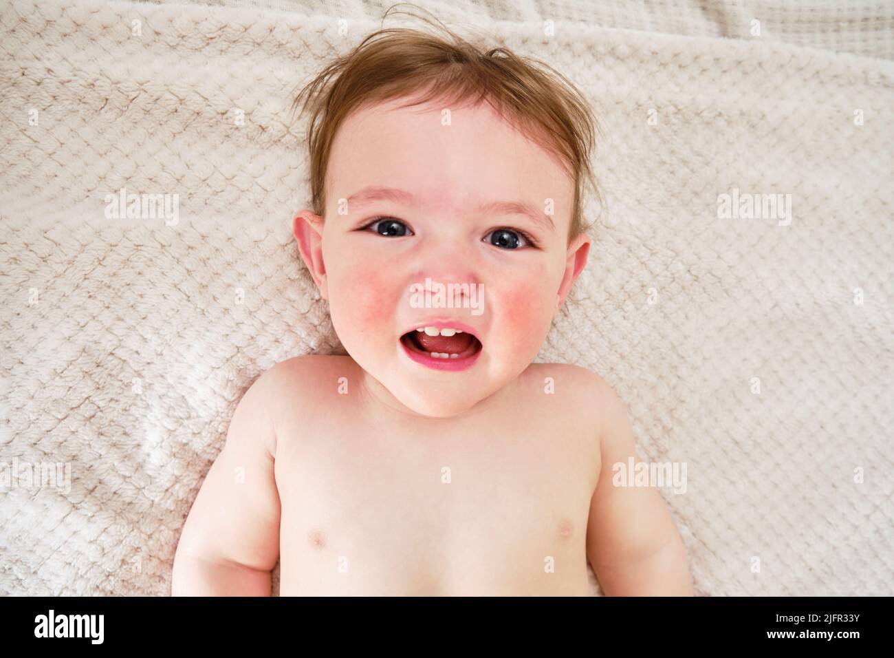 Crying screaming toddler baby boy is lying on the bed. Unhappy child ...