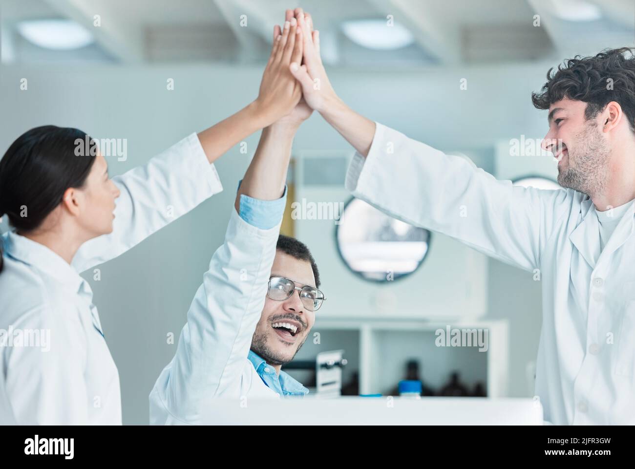 We aced the case. Shot of a group of young scientists giving each other ...