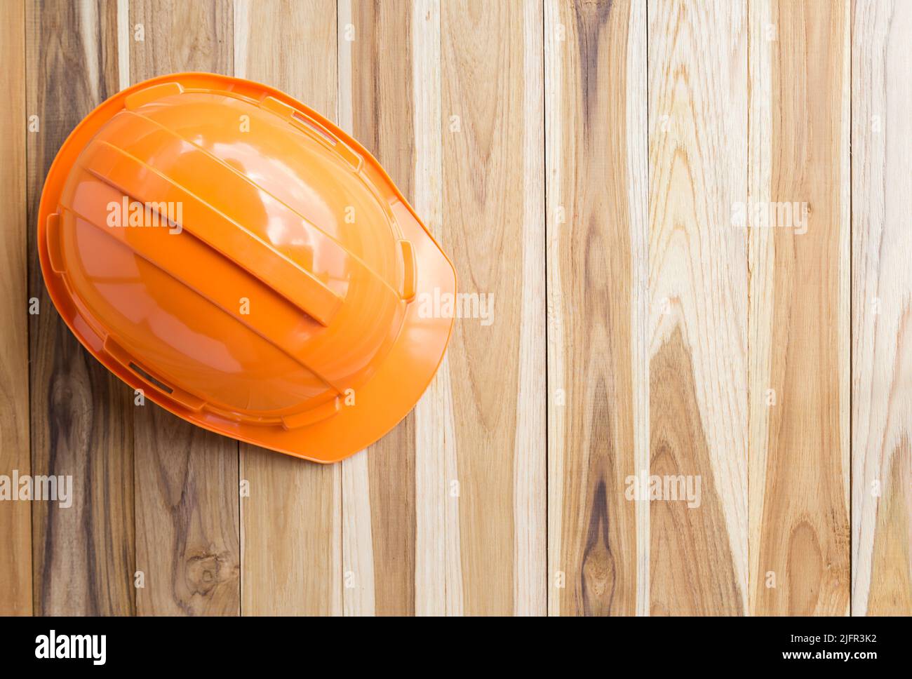 Orange safety engineer helmet gear on top of brown wooden table ...
