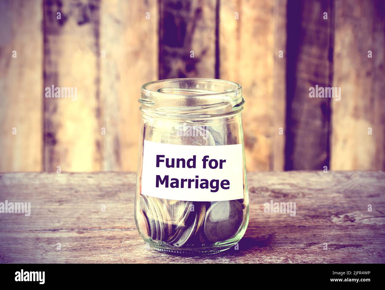 Coins in glass money jar with Fund for marriage label, financial ...