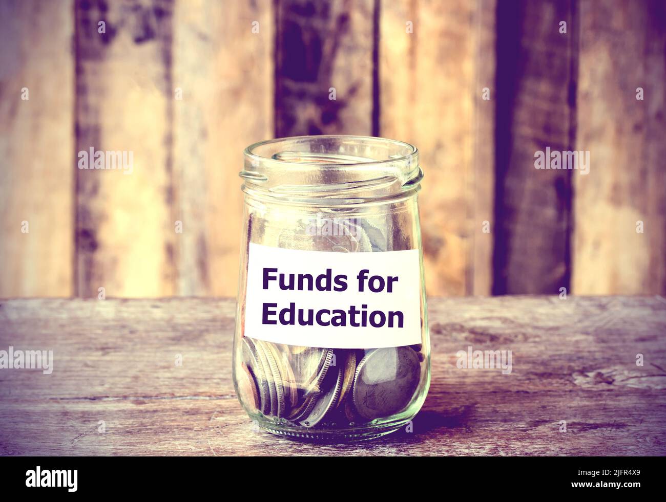 Coins in glass money jar with Funds for Education label, financial ...