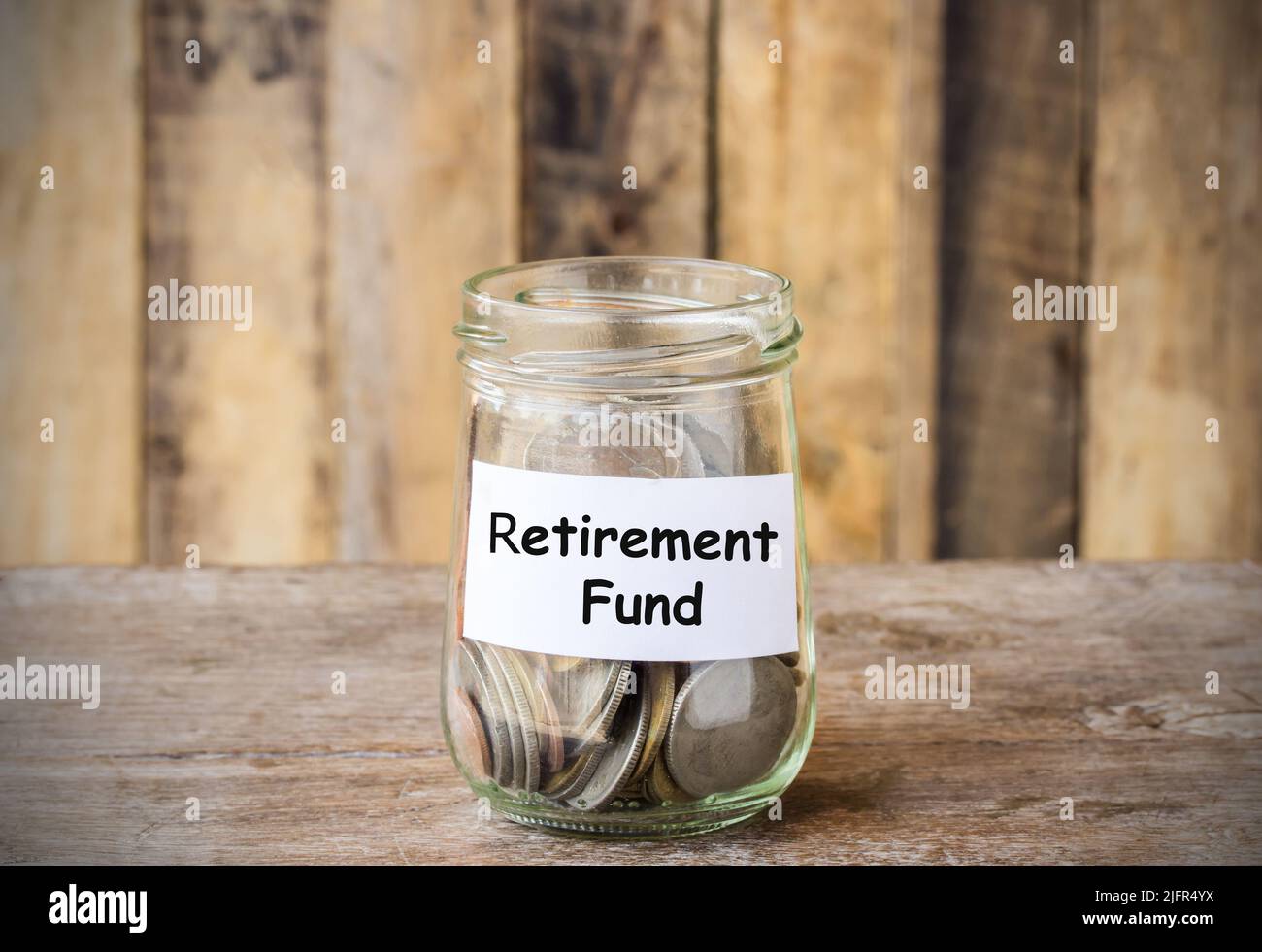 Coins in glass money jar with Retirement fund label, financial concept ...