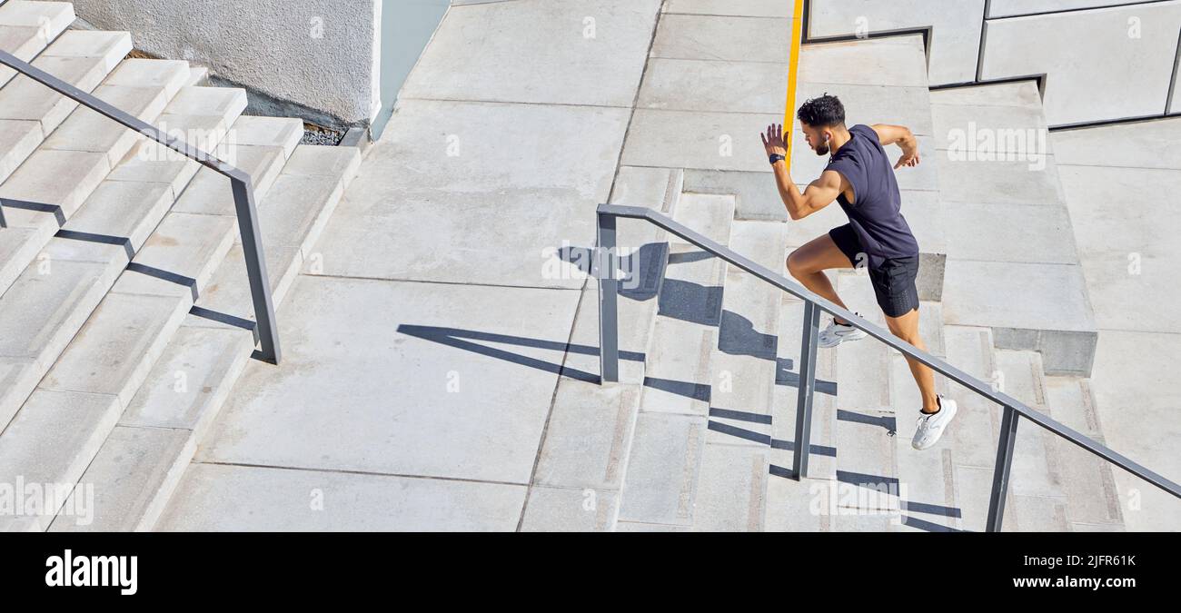 Race you to the top. High angle shot of a sporty young man running up a ...