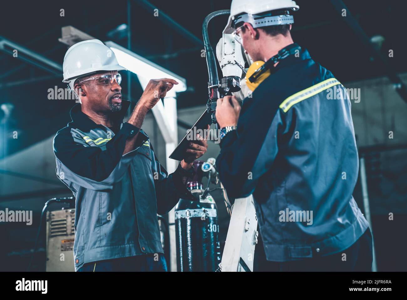 Factory workers working with adept robotic arm in a workshop . Industry ...