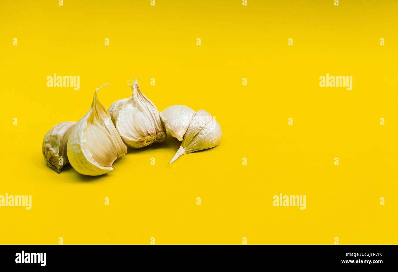 a few cloves of garlic on a yellow background isolated Stock Photo - Alamy