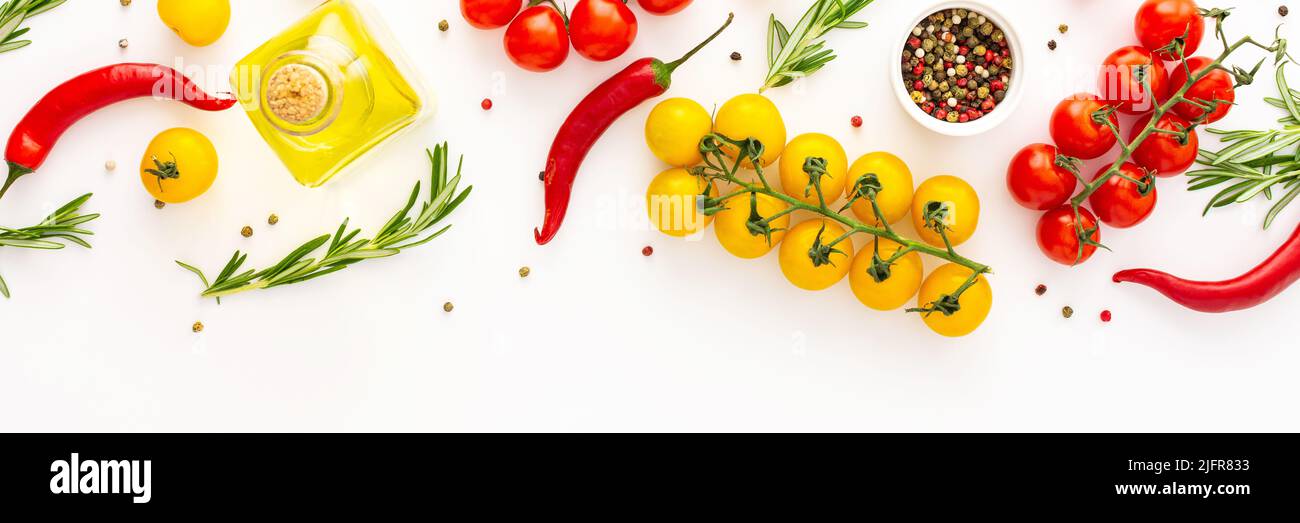 Yellow and red tomatoes, hot peppers, rosemary and spices on a white ...