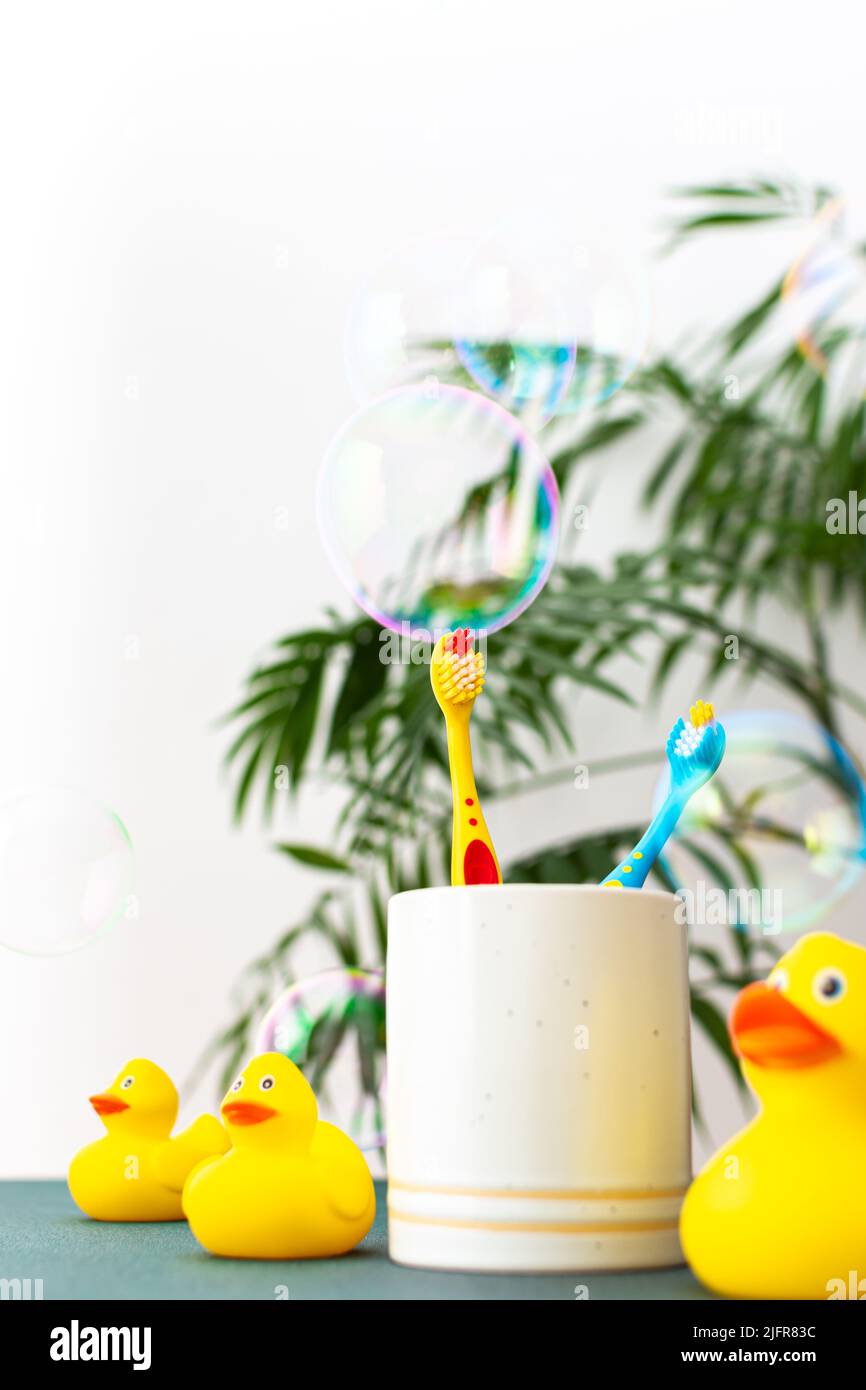Bright children's toothbrushes in a cup, rubber yellow ducks and soap ...