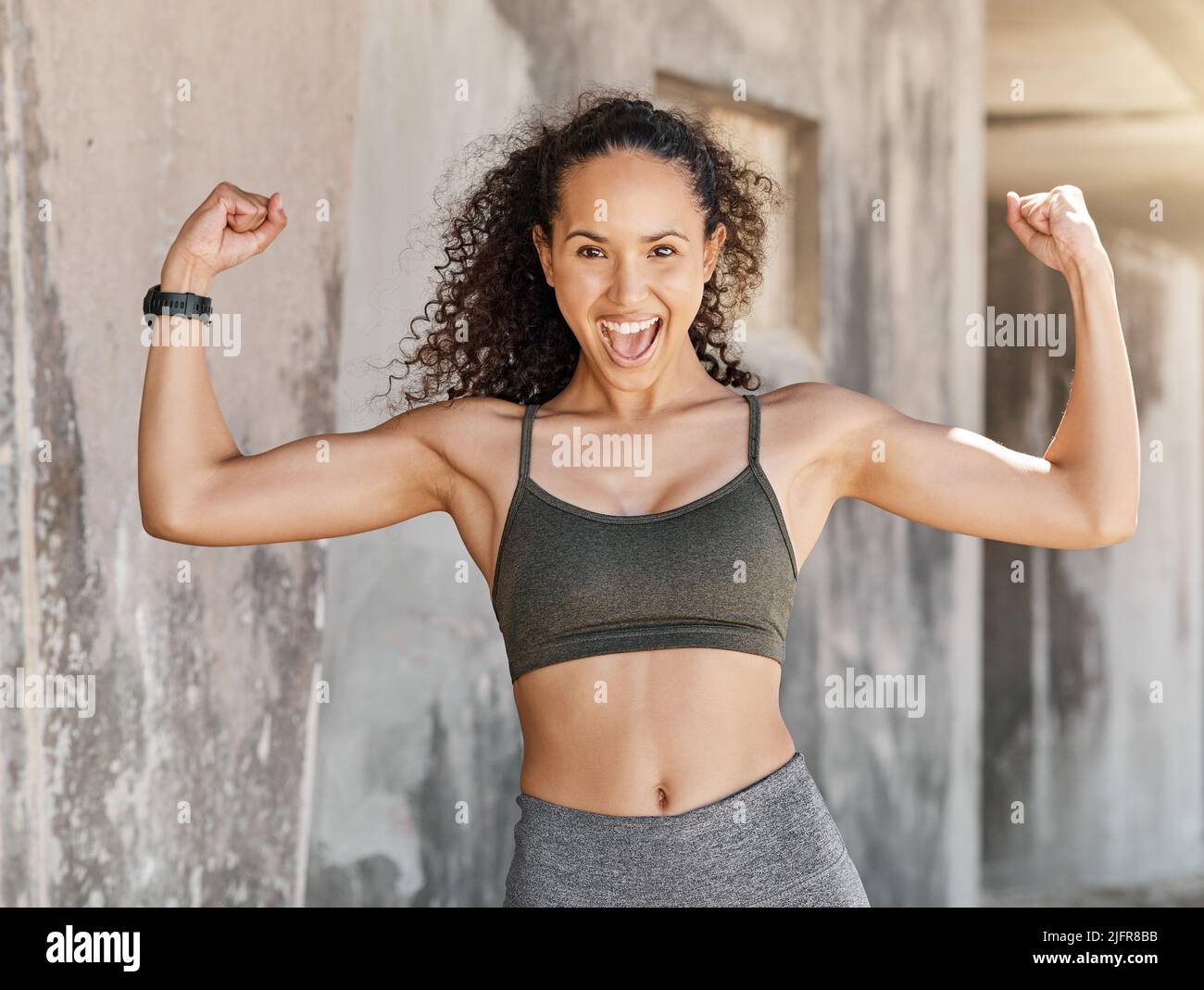 Check out my guns. Shot of an attractive young woman standing alone and ...
