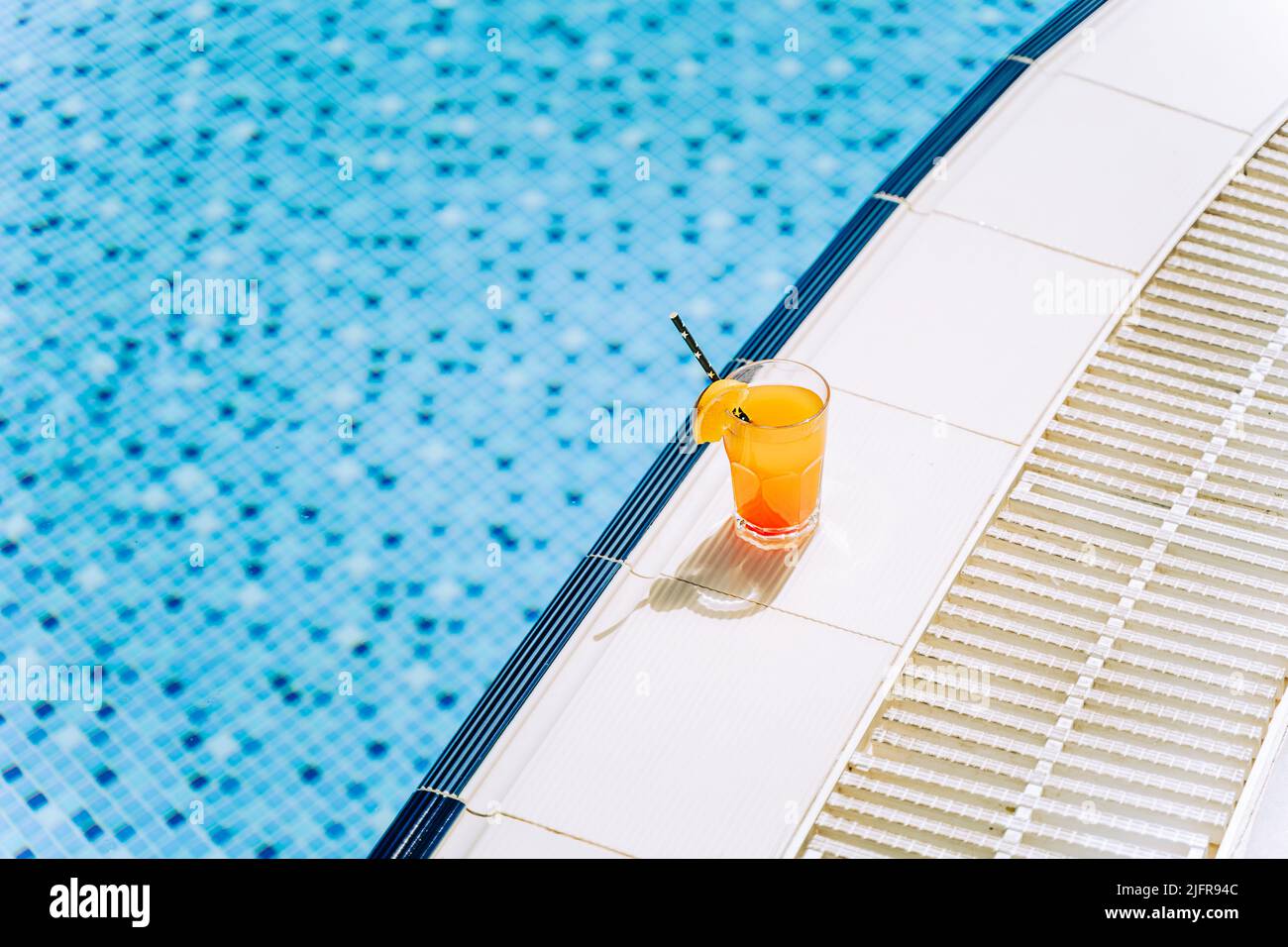 Tropical sparkling cocktail by the pool. The shot of glass with orange ...