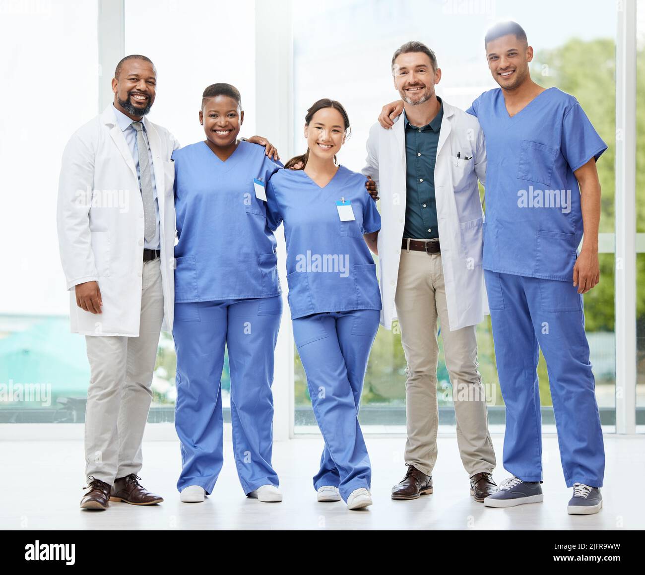 Together they save lives. Shot of a cheerful group of doctors standing ...
