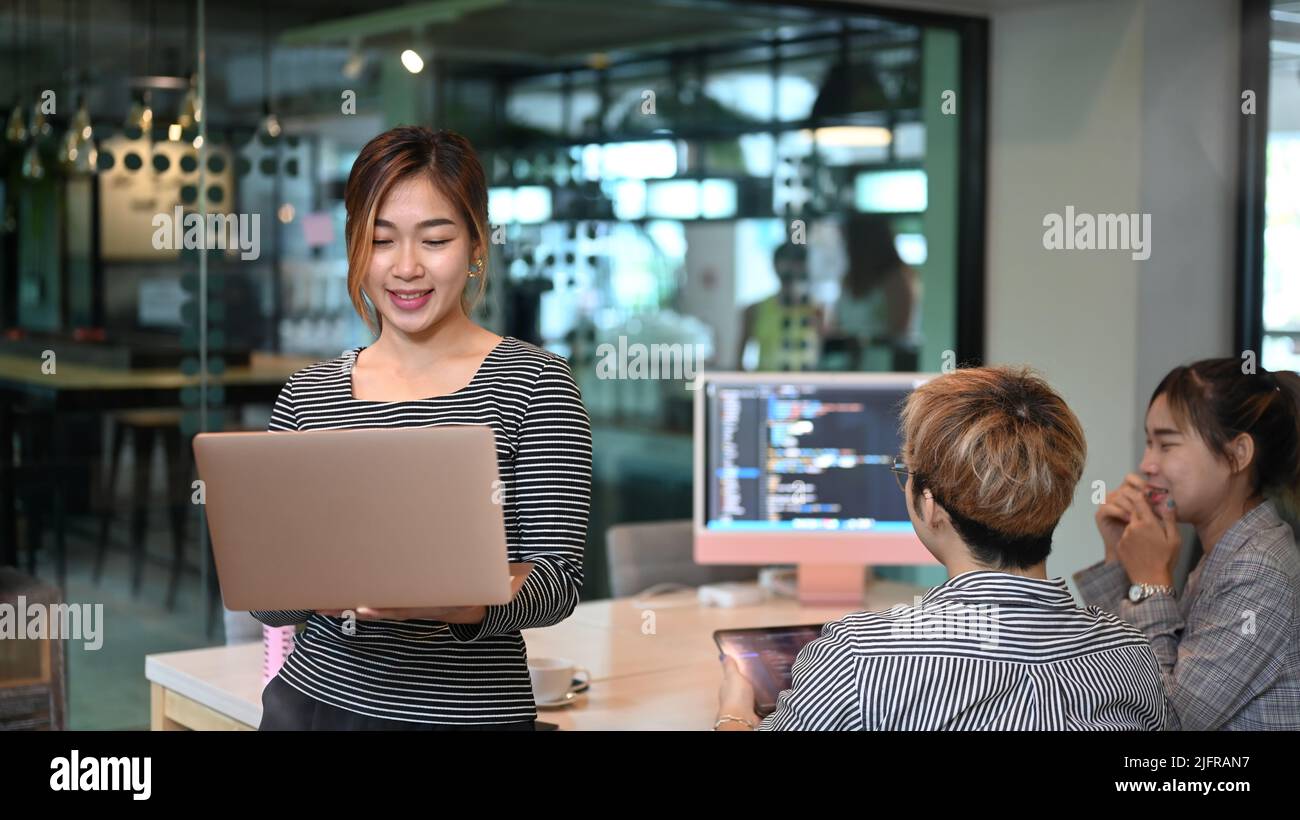 Asian female team leader standing in office and software developers ...