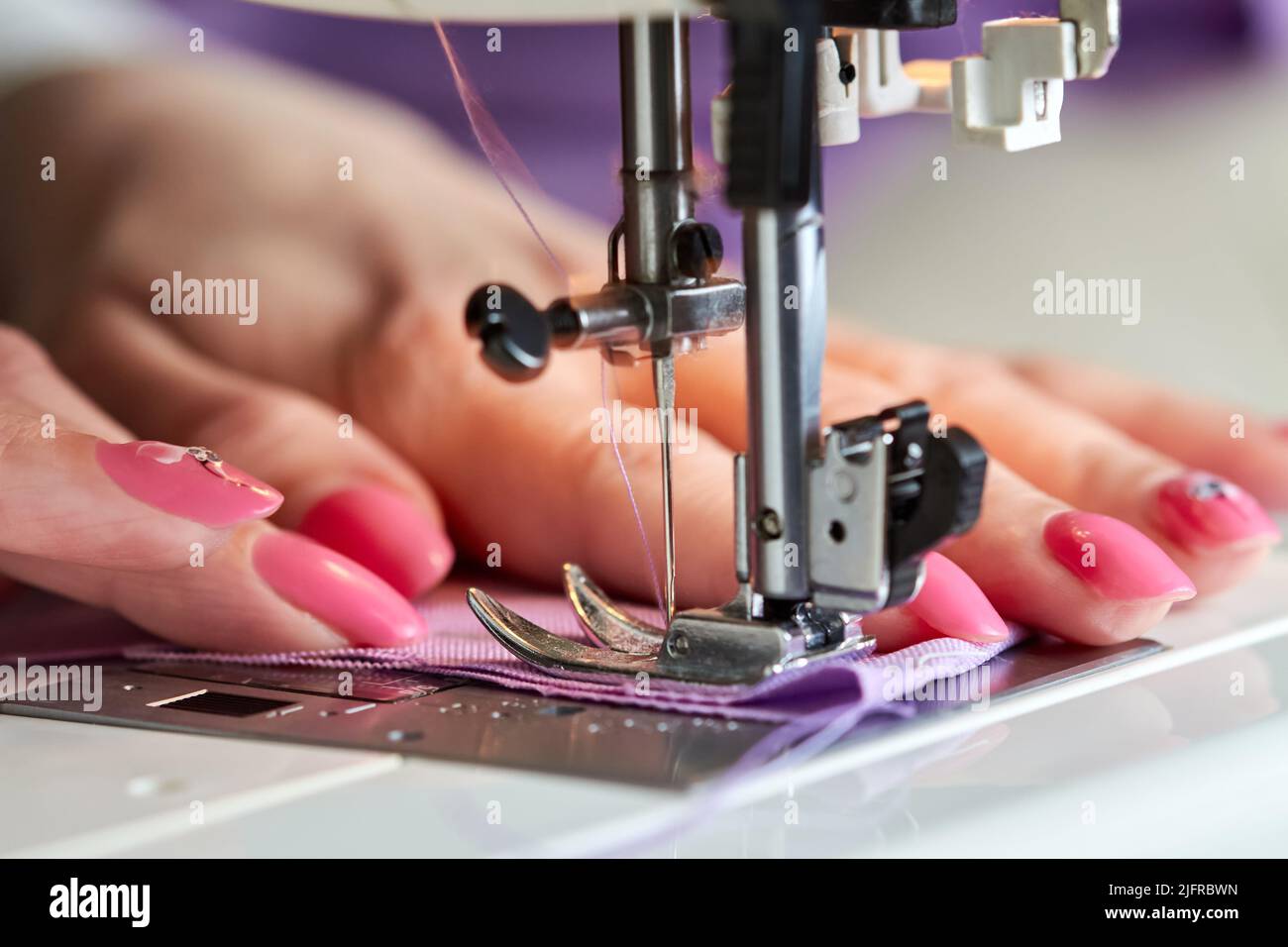 Woman sewing a dress on a sewing machine. Close-up, selective focus ...
