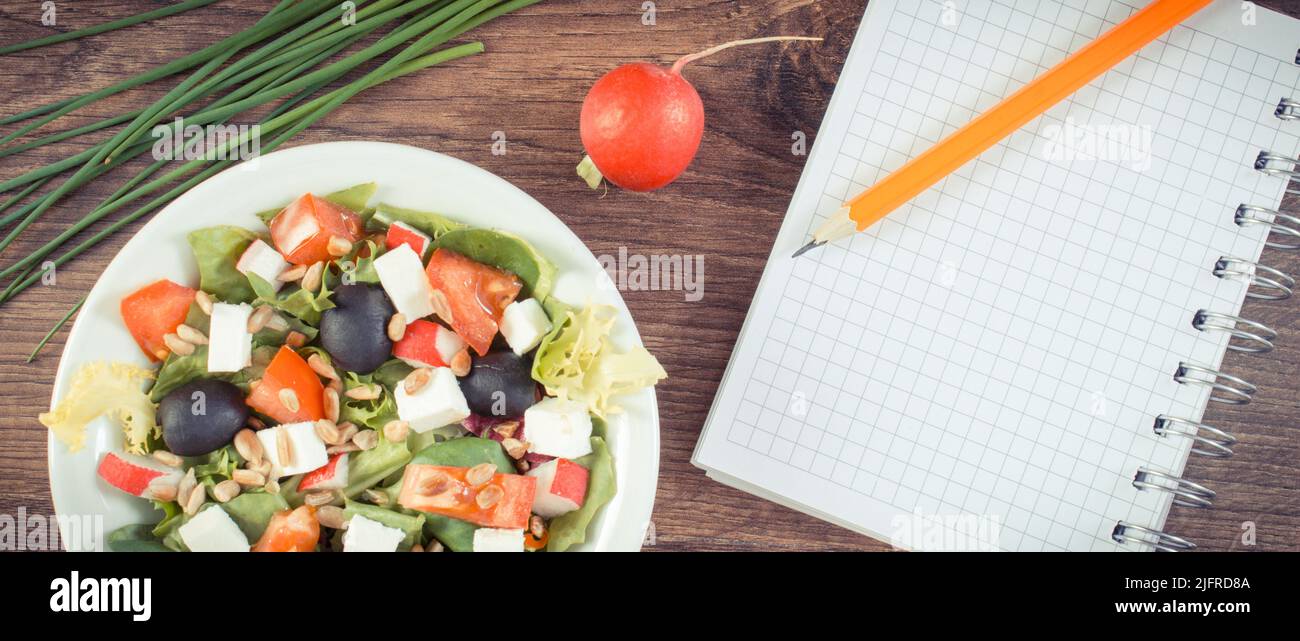 Fresh prepared greek salad with feta cheese and notepad for writing ...