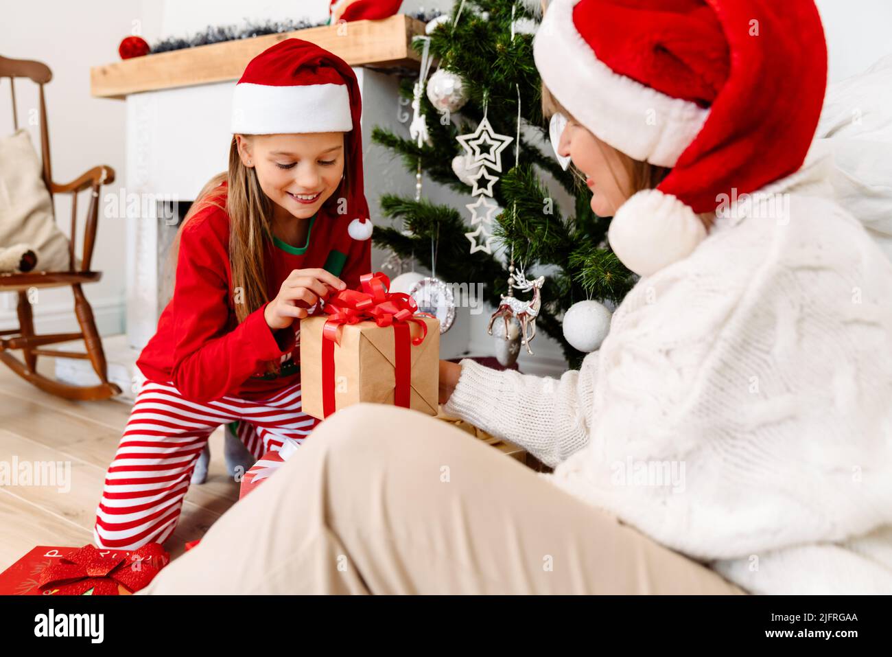 White family giving presents to each other by Christmas tree at home ...