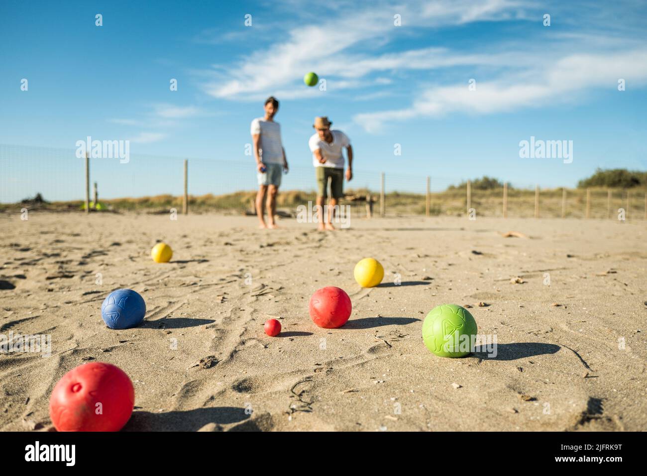 Tourists play an active game, petanque on a sandy beach by the sea ...