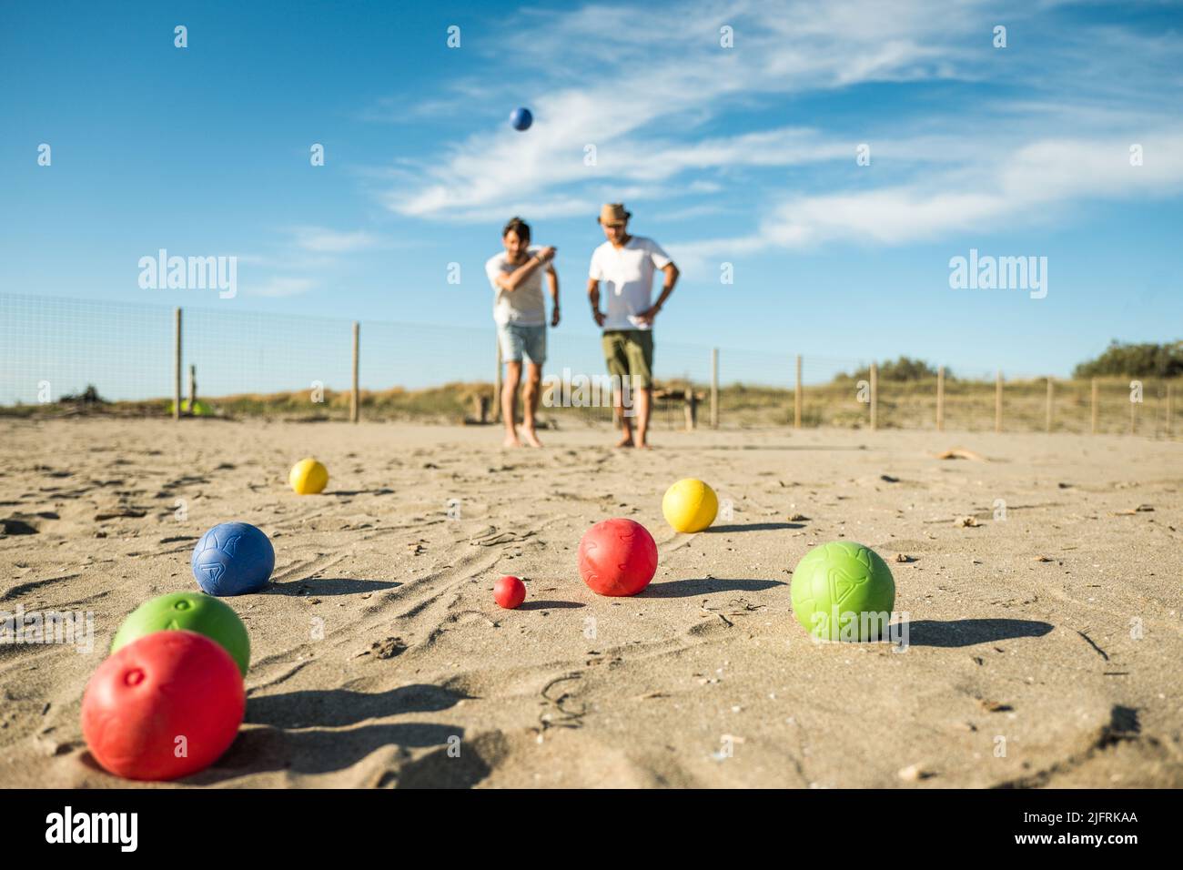Tourists play an active game, petanque on a sandy beach by the sea ...