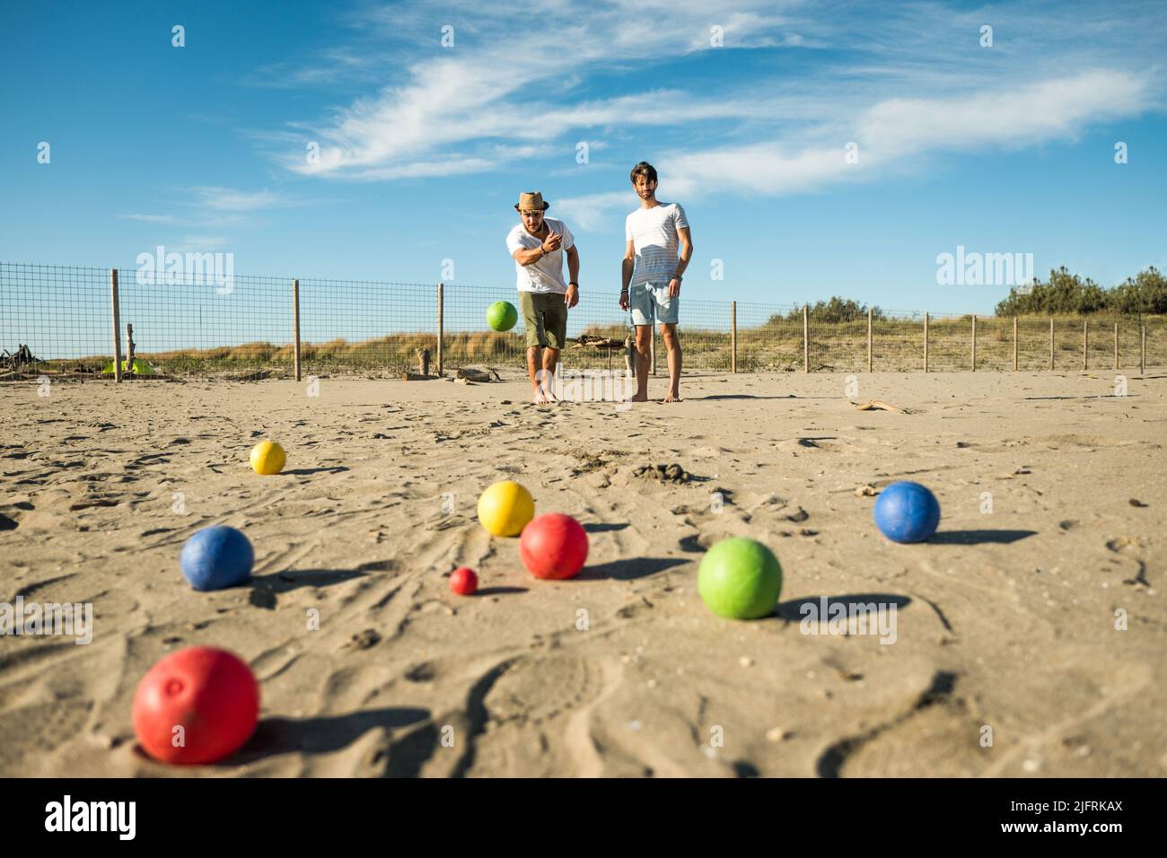 Tourists play an active game, petanque on a sandy beach by the sea ...