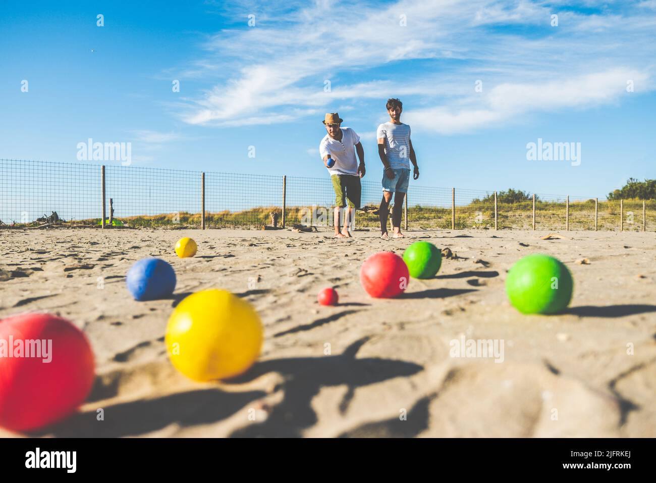 Tourists play an active game, petanque on a sandy beach by the sea ...