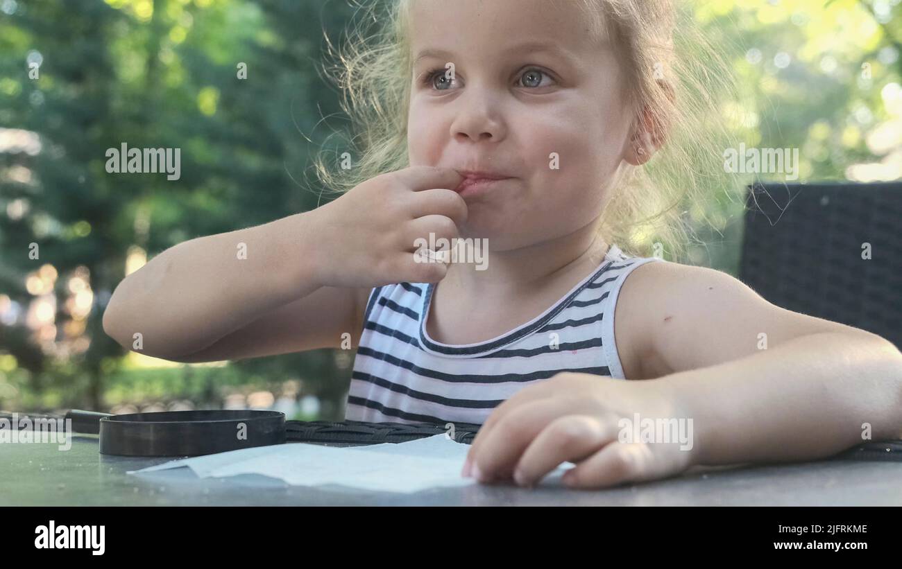 Little girl tastes salt. Close-up portrait of blonde girl takes salt ...
