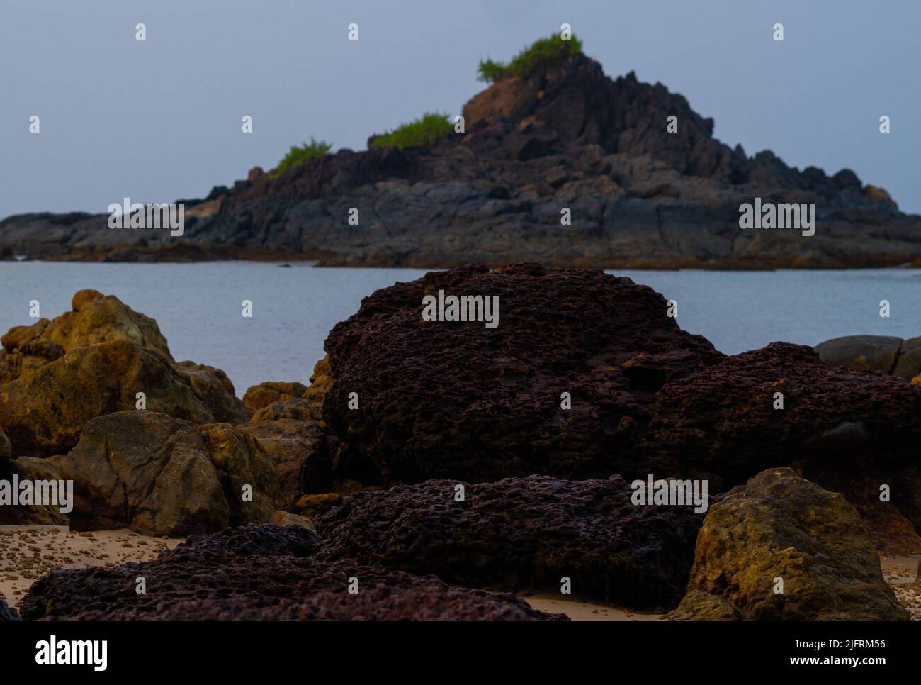 Sharpe purple rocks at seashore.Mossy grass on a rocks and beach in the ...
