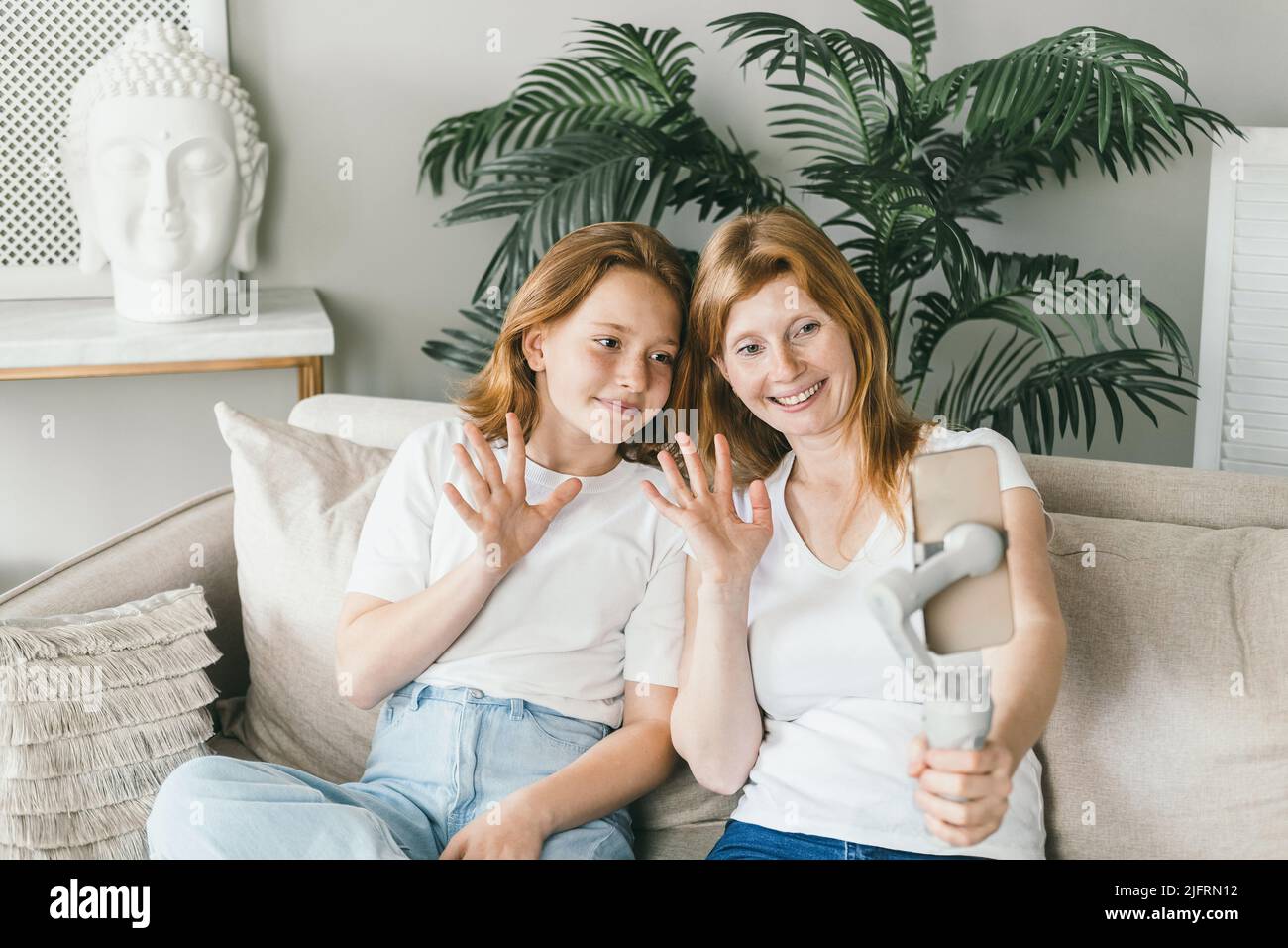 A teenage girl and a mother wave at the camera and smile Stock Photo ...