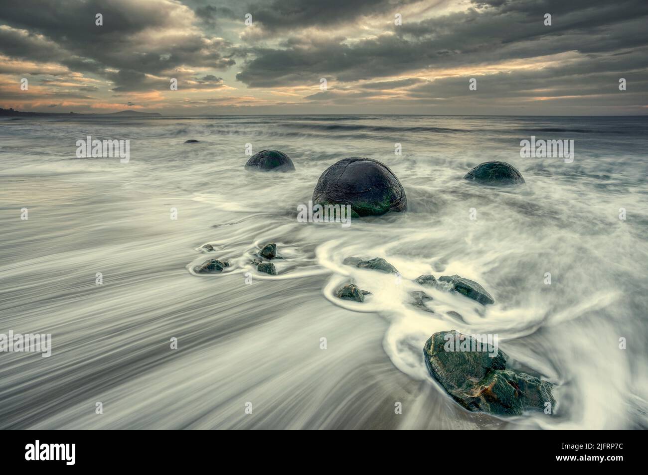 Dawn at Moeraki Boulder Beach. Large spherical boulders lying along a ...