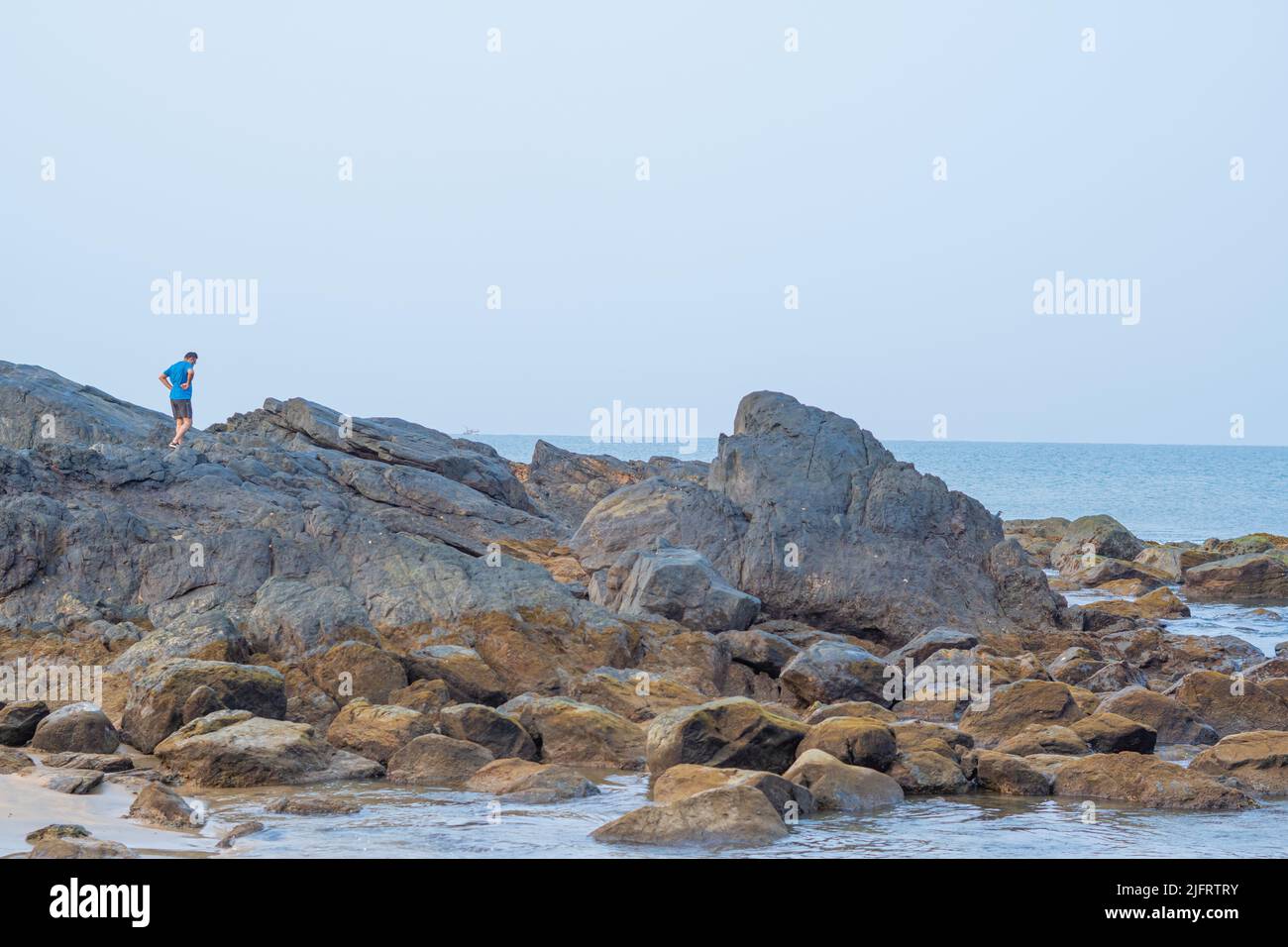 clear water,sea blue sky is clear,man walking on rocks Stock Photo - Alamy