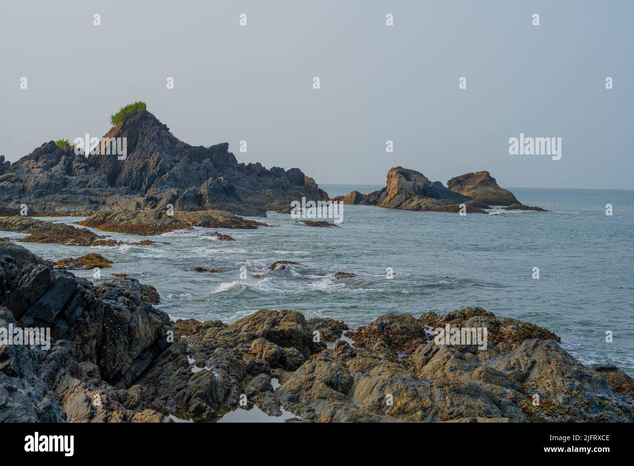 Small waves hitting rocks at beach, big rocks formation into the ocean ...