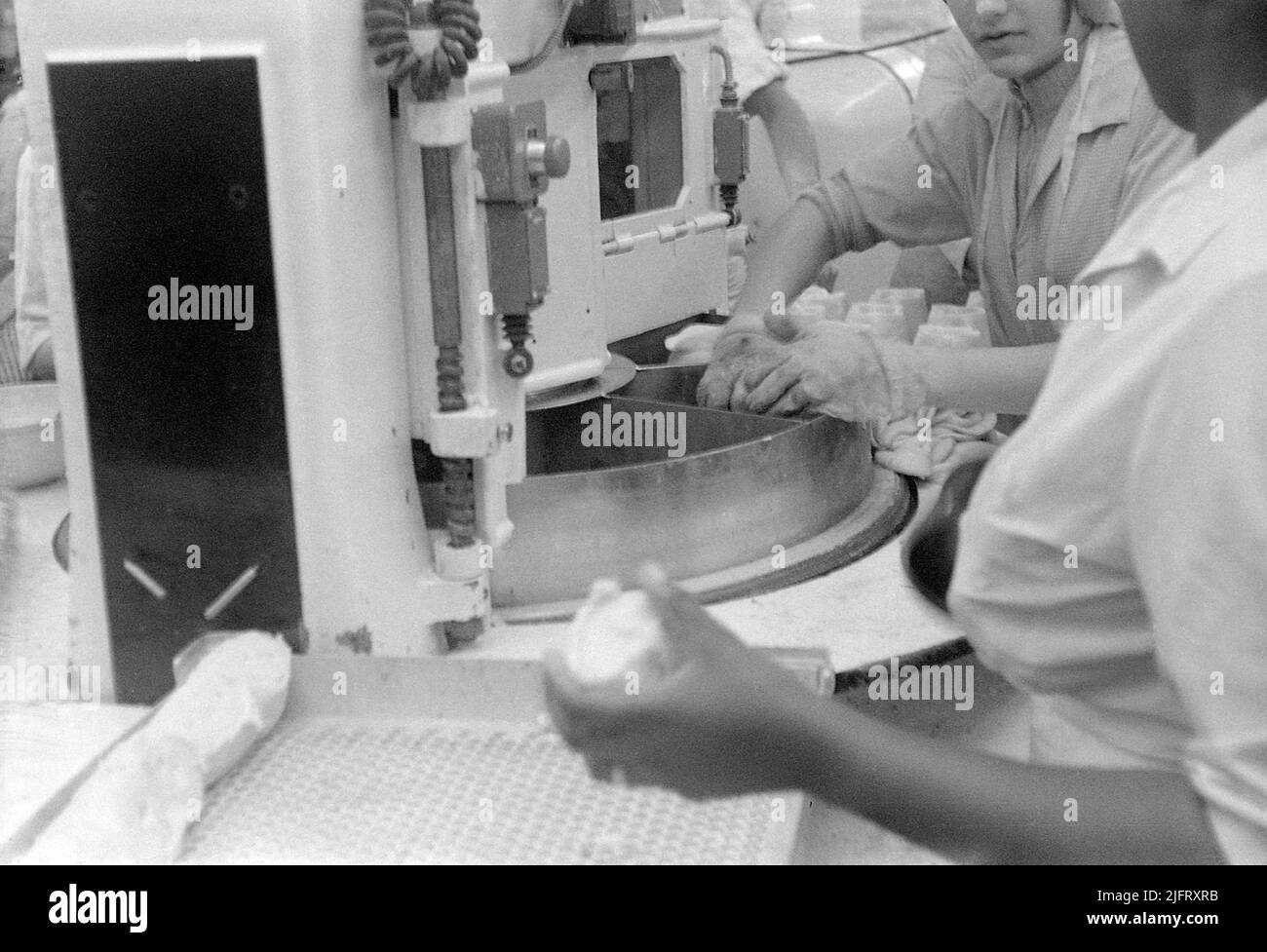 Two women operating an automatic pie press machine in a factory setting ...
