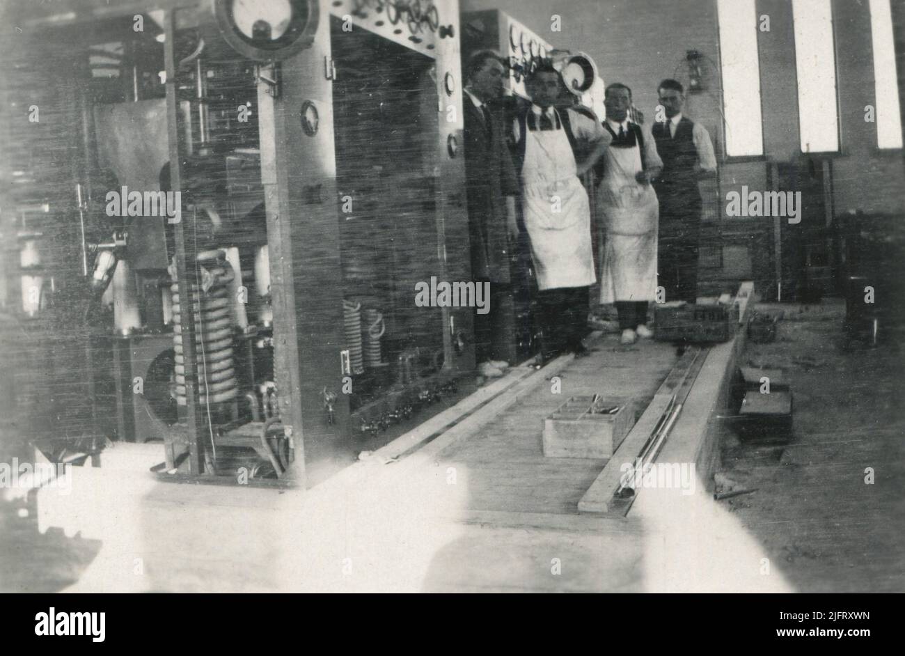 1930s. Engineers constructing equipment in a radio transmitting station ...