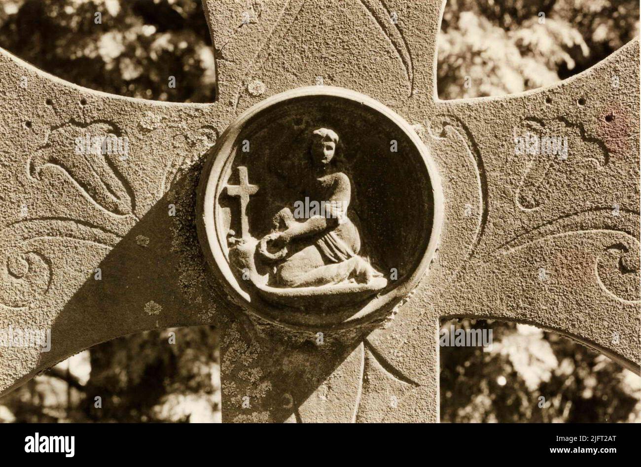 Cemetery. Tombstone in the form of a cross with centrally relief ...