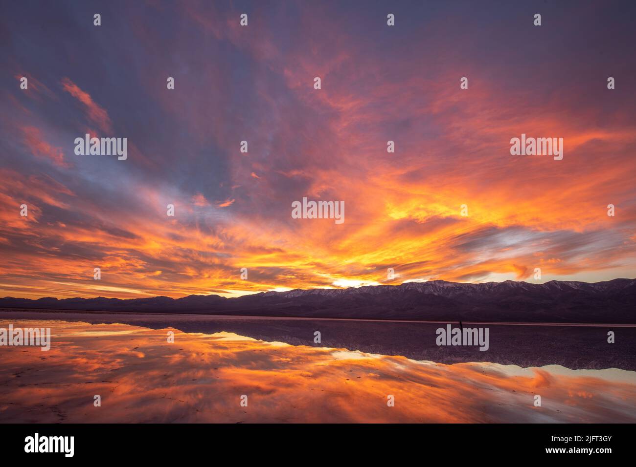 A mesmerizing scene of dramatic orange cloudy sky reflect on lake water ...