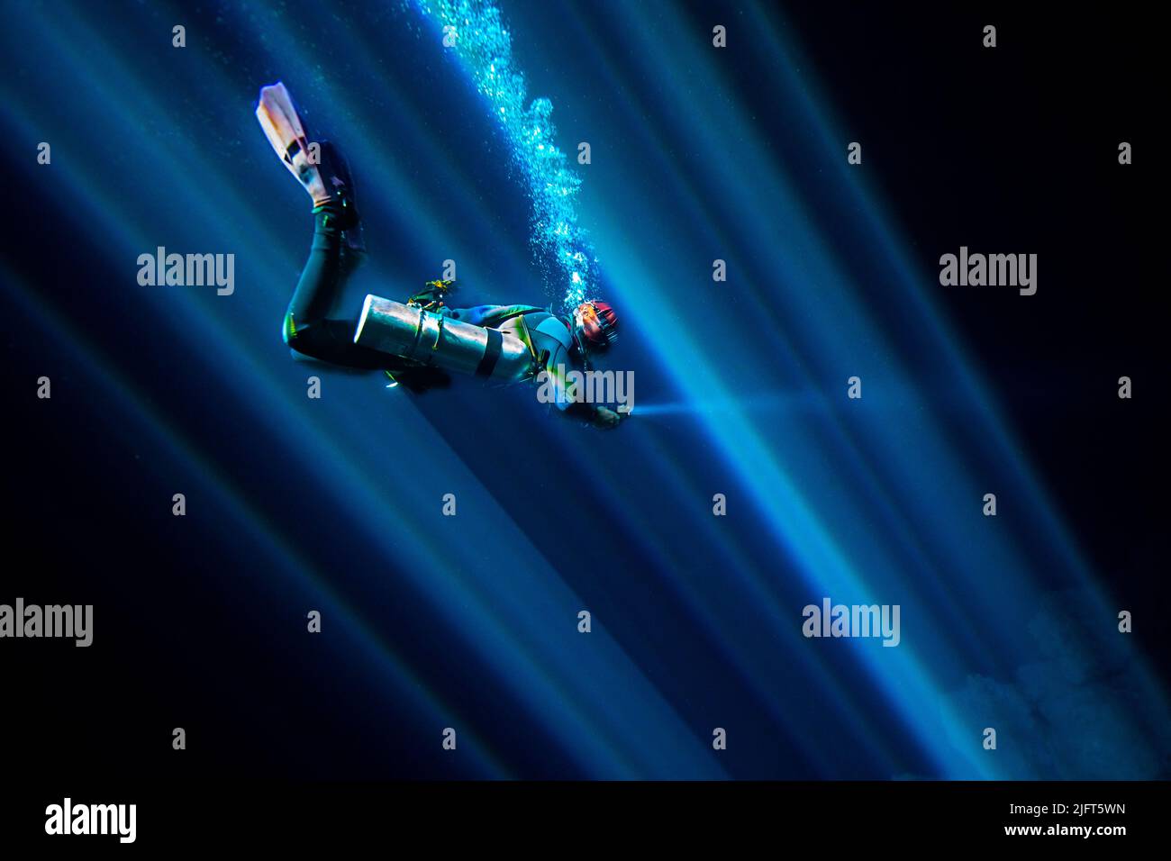 A breathtaking view of scuba diver with flashlight in the deep ocean ...
