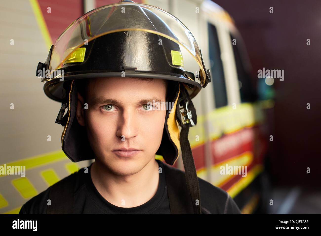 Firefighter in uniform and helmet stand in behind of fire truck Stock ...