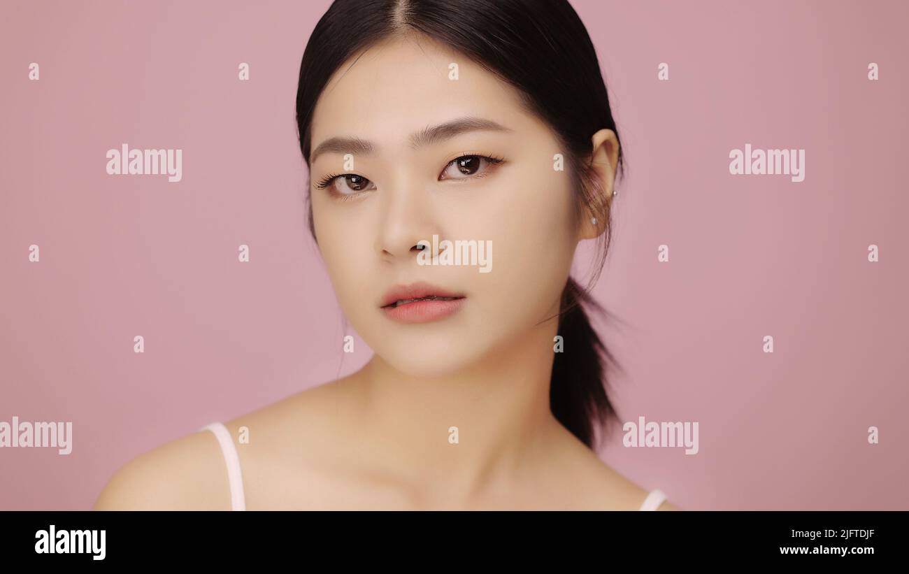 Close up face of beautiful young Asian woman with clear skin on pink ...