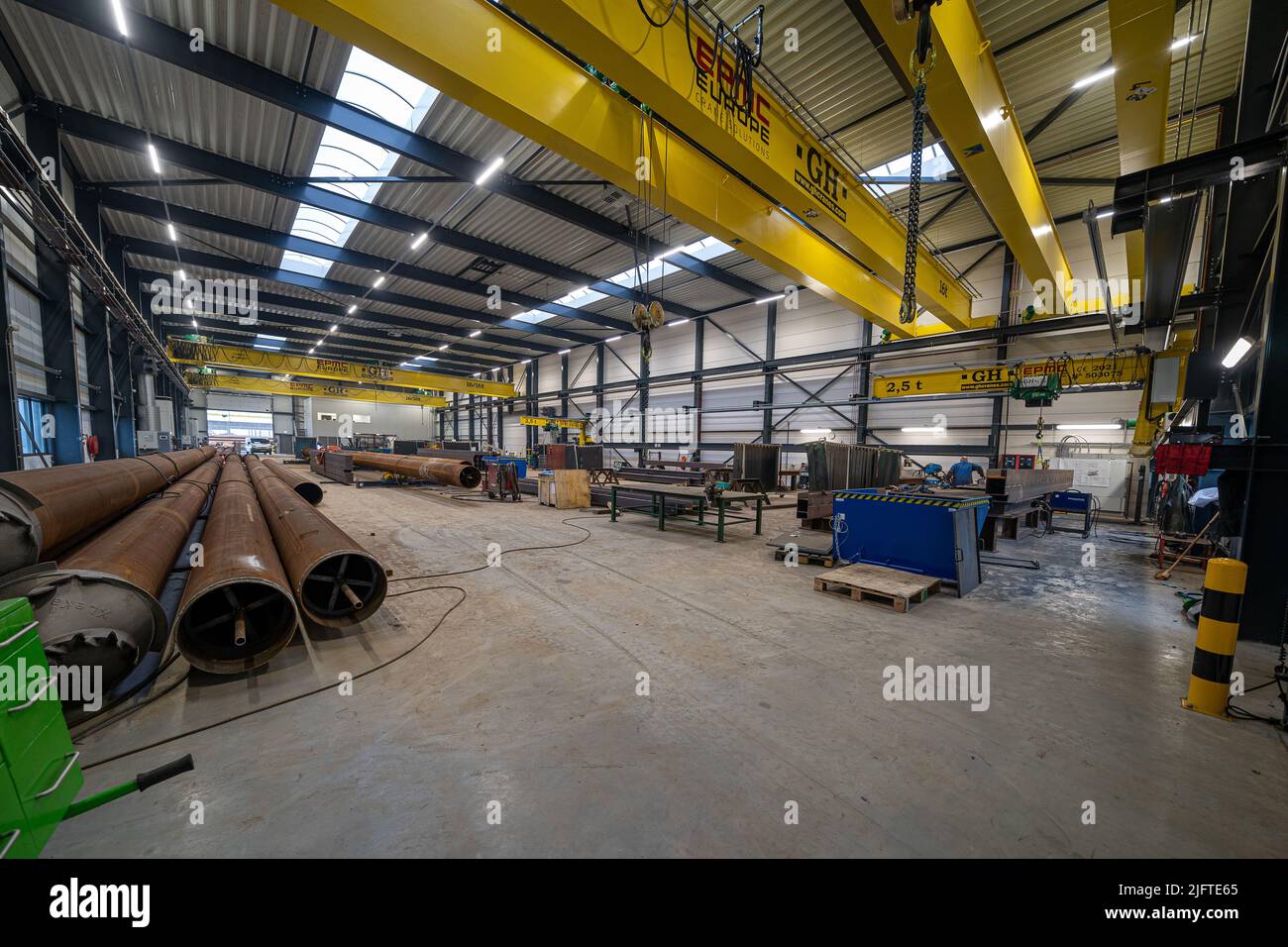 Interior of a steel factory with mobile cranes, steel piles and beams ...
