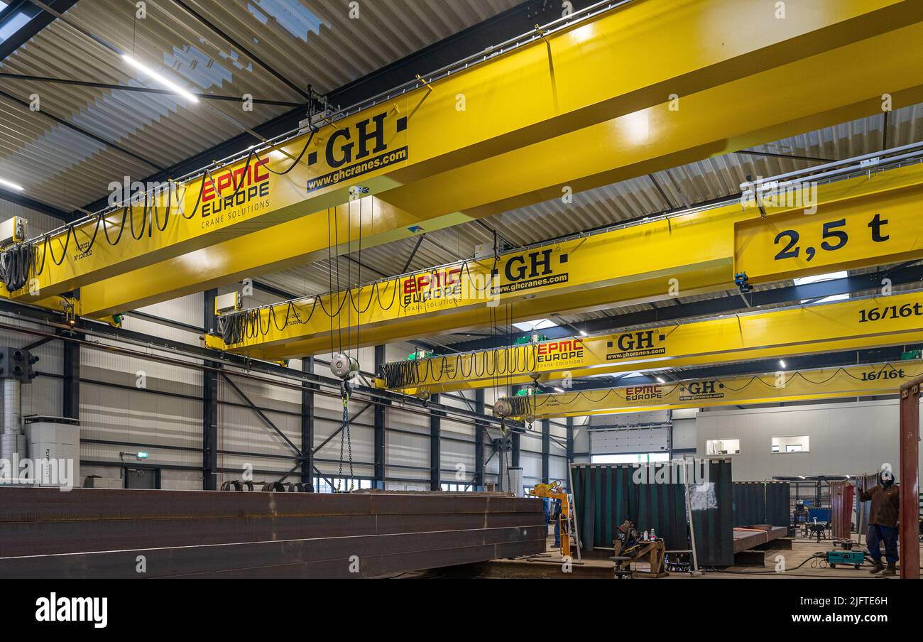 Interior of a steel factory with mobile cranes, steel piles and beams ...