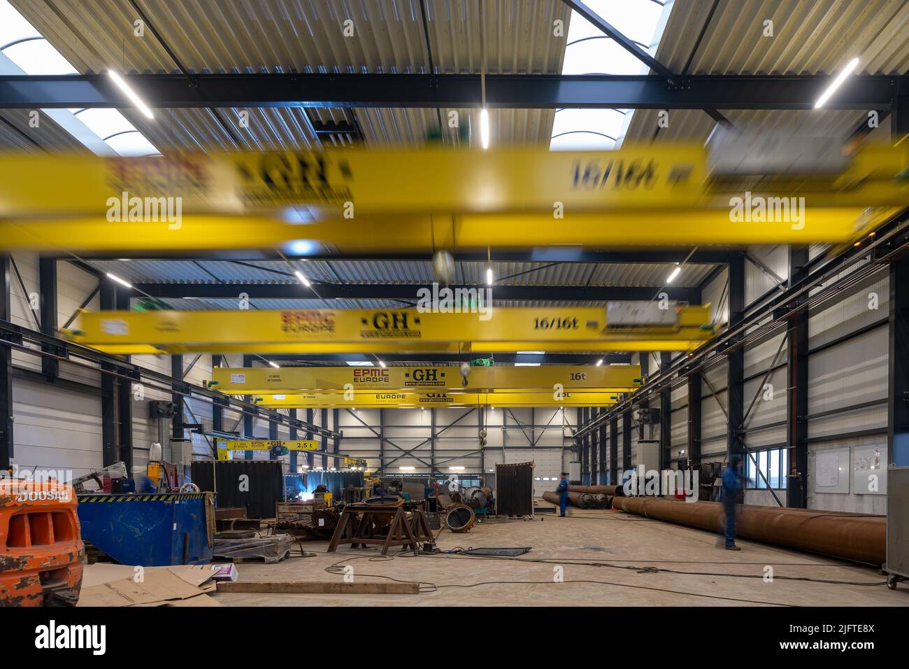 Interior of a steel factory with mobile cranes, steel piles and beams ...