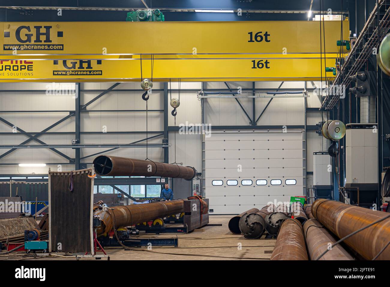 Interior of a steel factory with mobile cranes, steel piles and beams ...