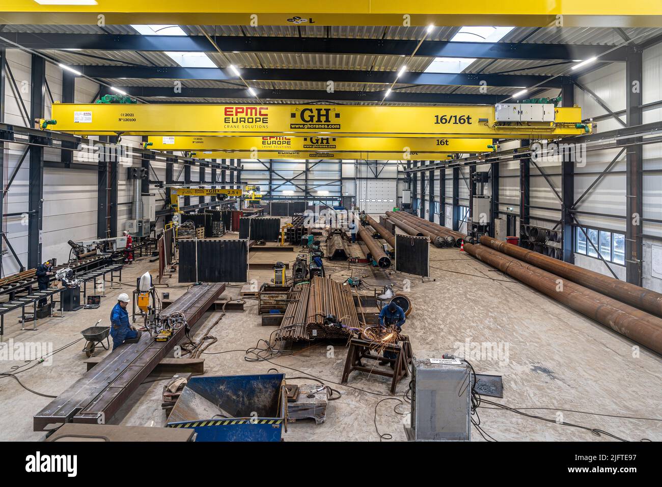 Interior of a steel factory with mobile cranes, steel piles and beams ...