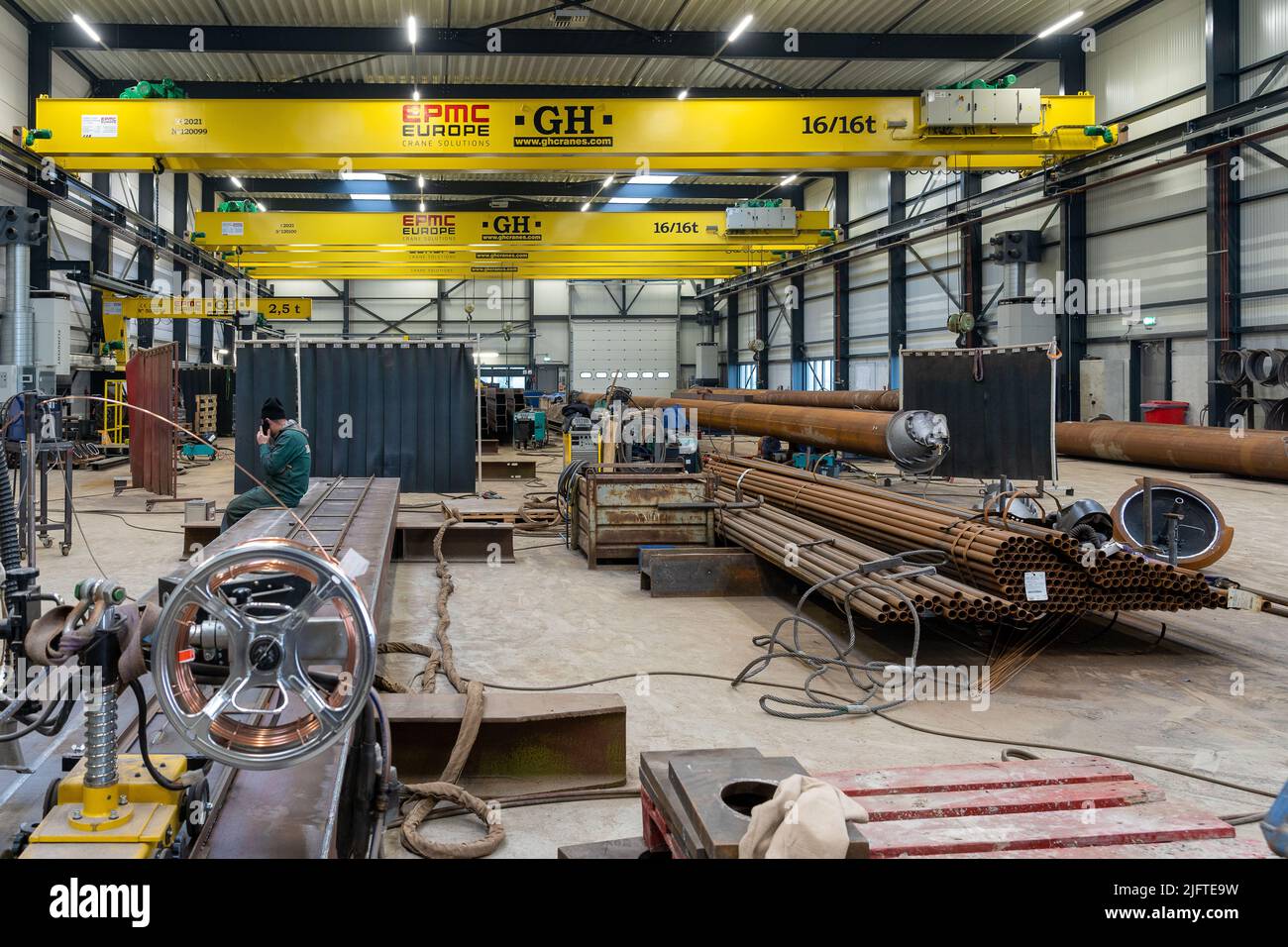 Interior of a steel factory with mobile cranes, steel piles and beams ...