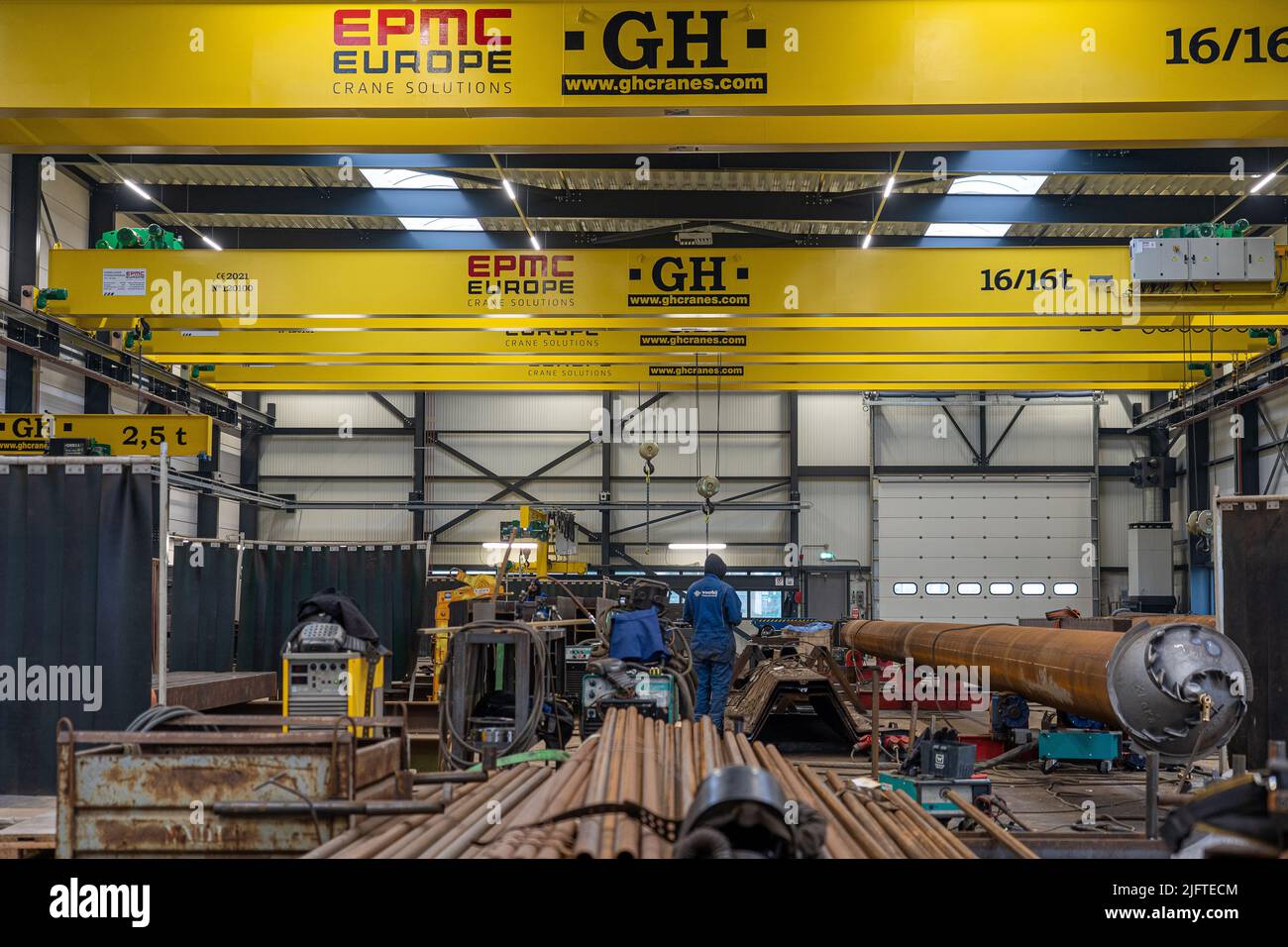 Interior of a steel factory with mobile cranes, steel piles and beams ...