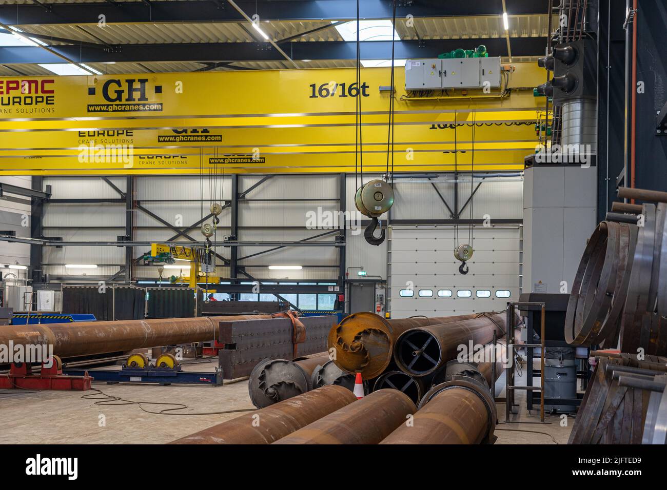 Interior of a steel factory with mobile cranes, steel piles and beams ...