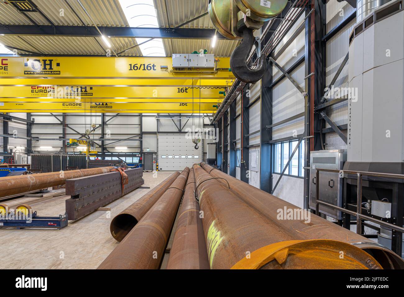 Interior of a steel factory with mobile cranes, steel piles and beams ...