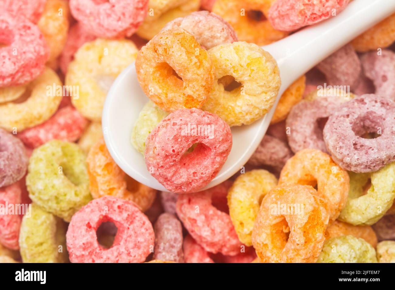 Fruit flavor colored cereals and a white spoon in a close up view Stock ...