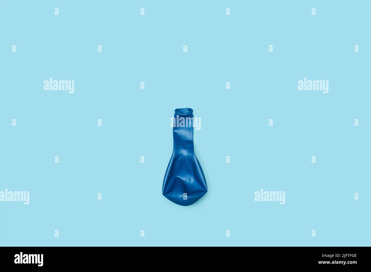 A deflated blue balloon on a blue background with copy space Stock ...