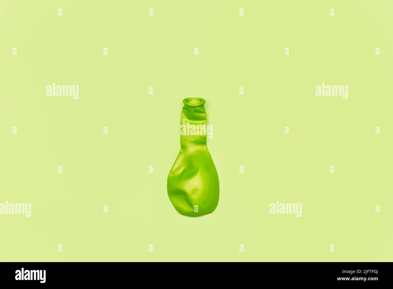A deflated green balloon on a green background with copy space Stock ...