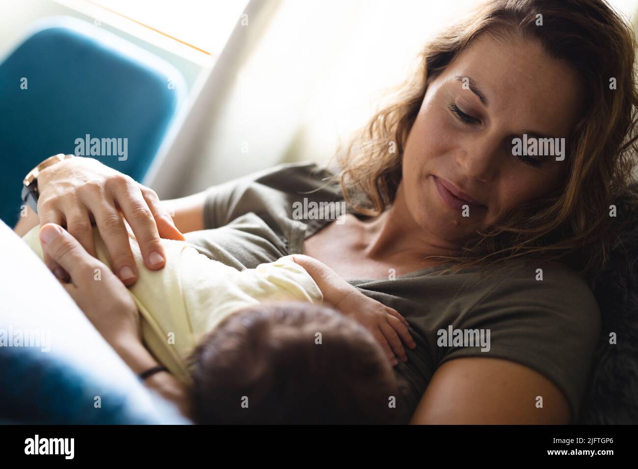 Loving mid adult caucasian mother breastfeeding newborn baby at home ...