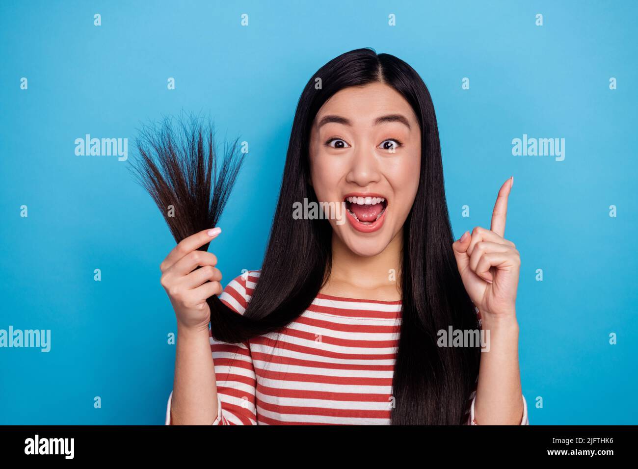 Photo of overjoyed pretty indonesian girl point finger hold demonstrate ...