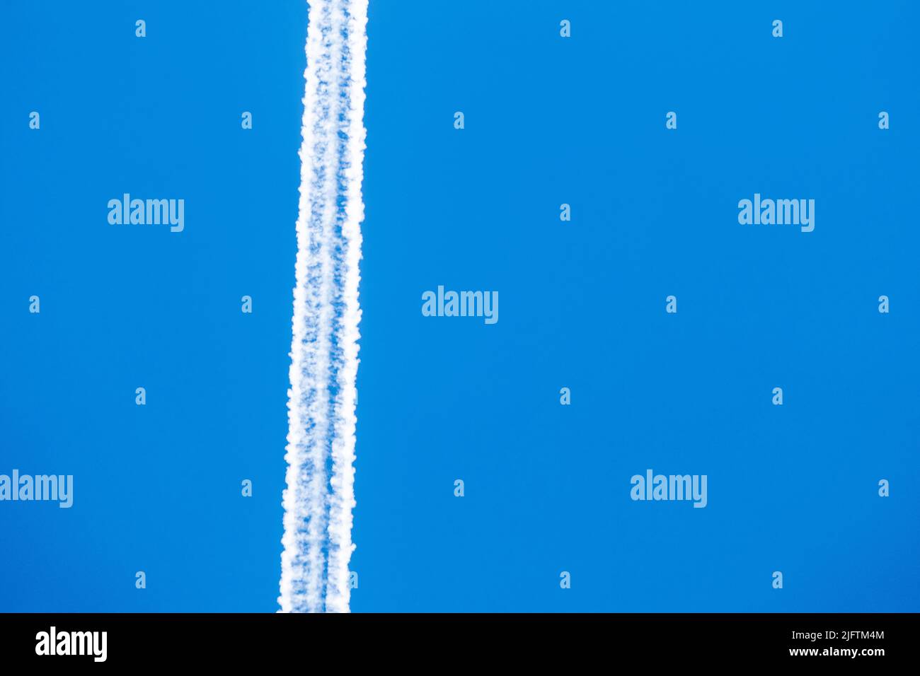 A low angle shot of long white trail of jet plane on blue sky Stock ...